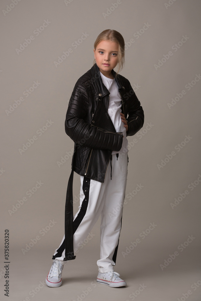 Beautiful little girl child in a leather jacket posing in the studio ...