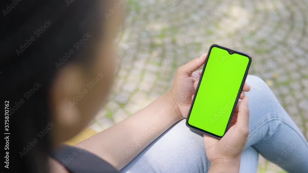 A black woman looks at a smartphone with green screen - vertical ...