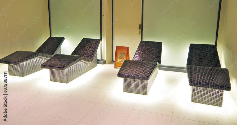 Thermal suite with heated loungers or relaxation chairs in spa or ...