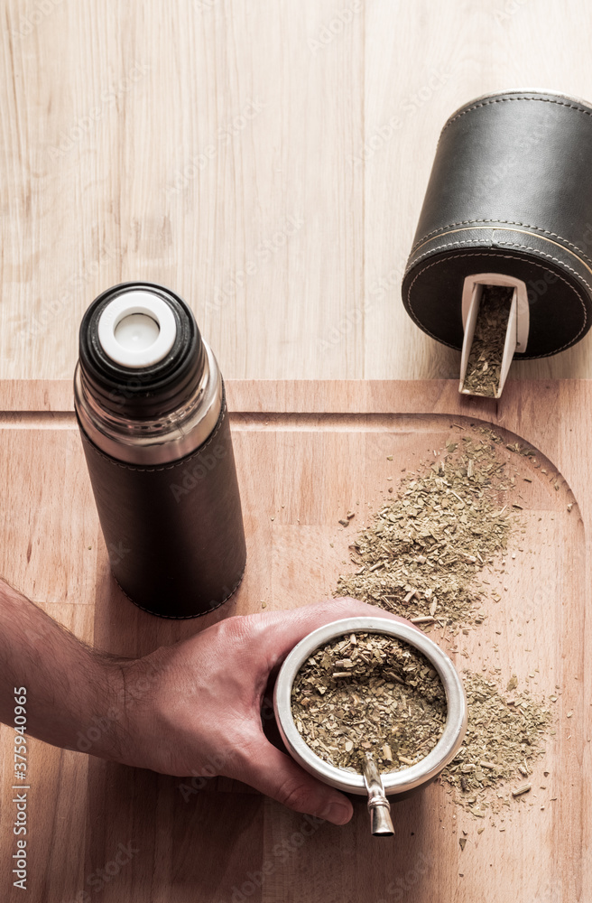 Mano de hombre sosteniendo un Mate, fondo con los elementos del juego ...