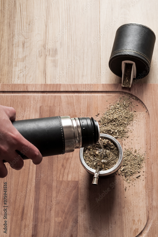 Mano de hombre cebando un Mate, fondo con los elementos del juego ...