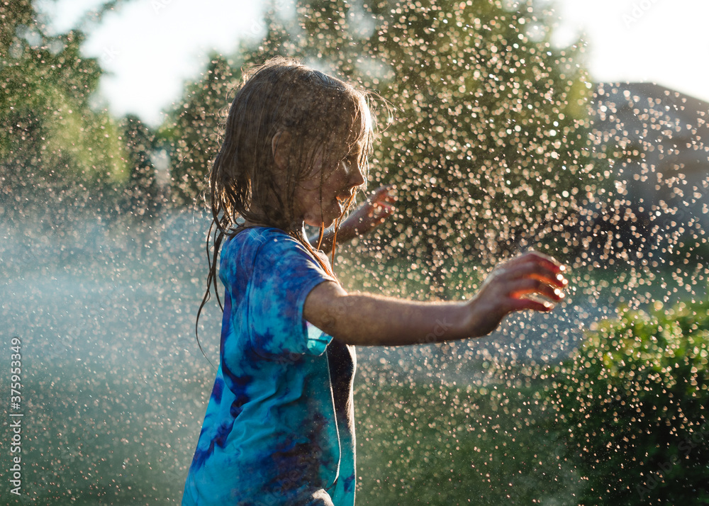 Little girl playing in the sprinklers foto de Stock | Adobe Stock
