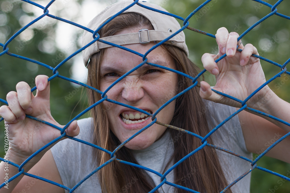 creepy zombie in cap looks throught the iron net Stock Photo | Adobe Stock