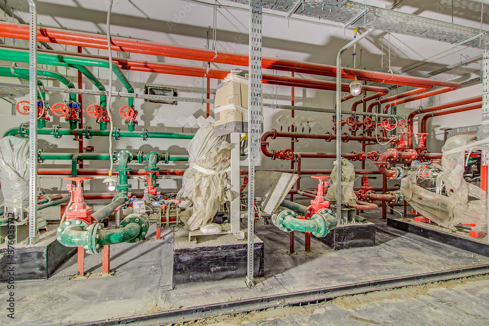 Mounting red and green piping. Installation of fittings in basement of ...