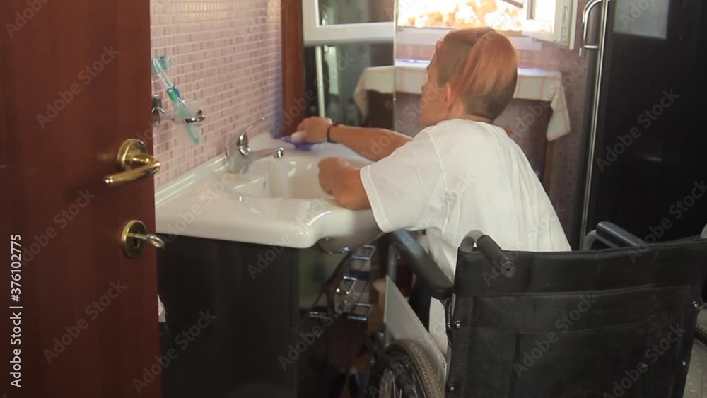 daily life of a disabled person in a wheelchair in the bathroom washing ...