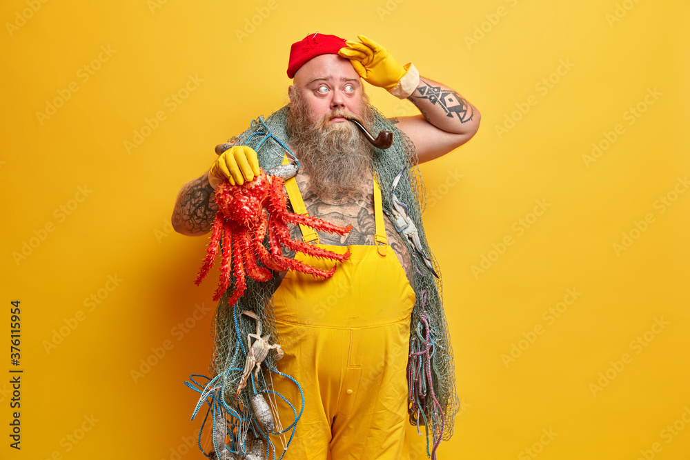 Shocked plump bearded man stares into distance, keeps hand on forehead ...