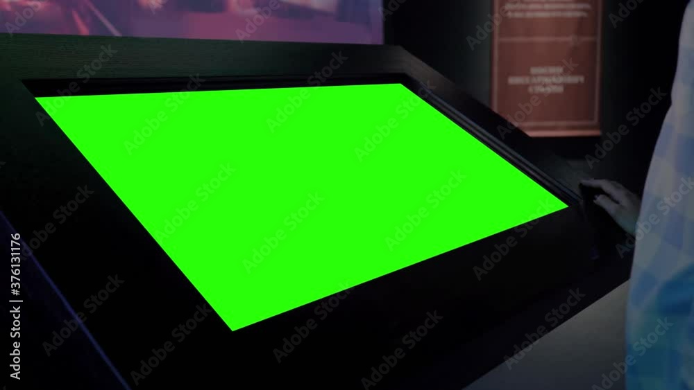 Woman looking at blank digital interactive green display kiosk at ...