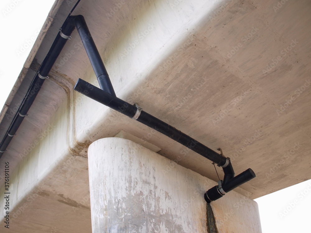 Drain pipes under a highway bridge. Black plastic pipes are installed ...