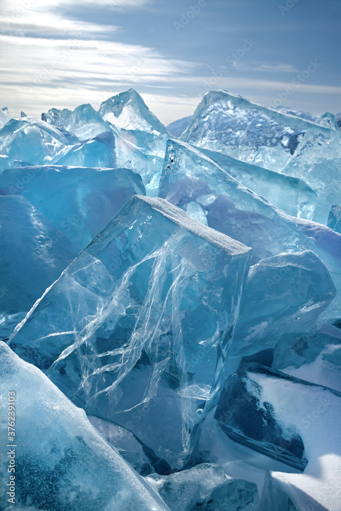 Beautiful transparent blue ice block with cracked structure among field ...