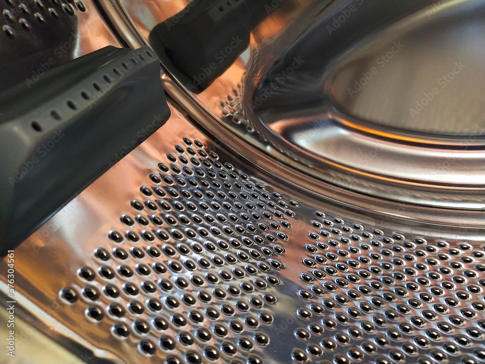 The drum of the washing machine from the inside. Shiny metal tank with ...