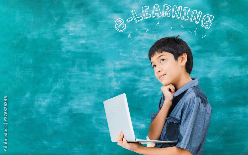 Asian happy school boy thinking and holding laptop on black board with ...