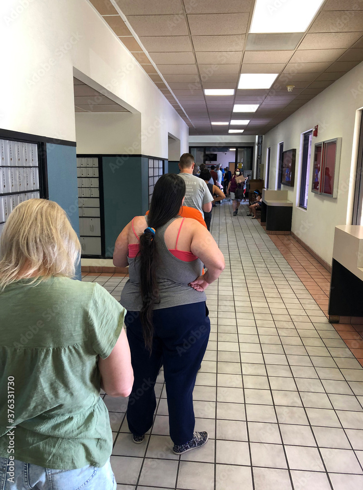 People waiting in a long line inside the foyer of the USPS building ...