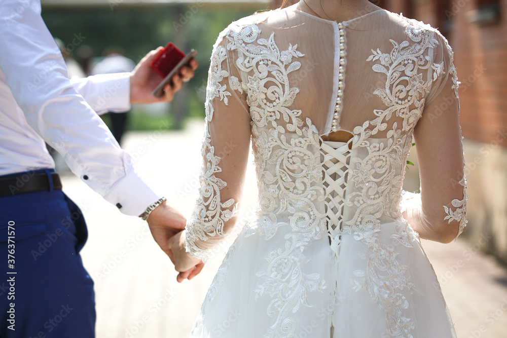 Back of the bride in a white wedding dress close-up. Bride fees ...