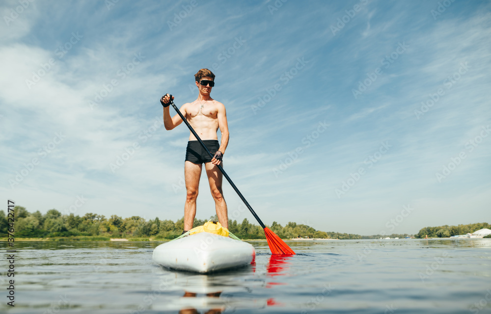 Fotografia do Stock: Handsome young man standing on sup board with ...
