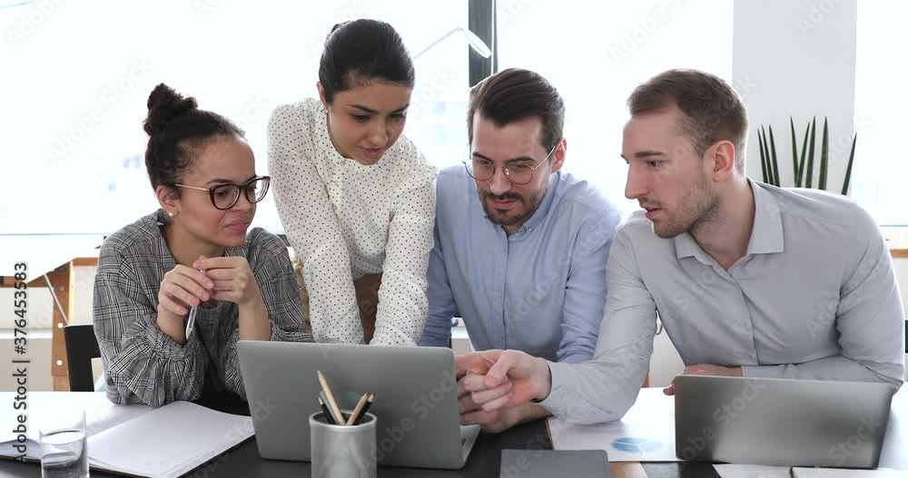 Multi ethnic colleagues staff members gather in modern office boardroom using computer ...
