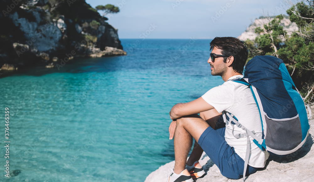 Indian male hiker resting at rocky abyss with breathtaking scenery ...