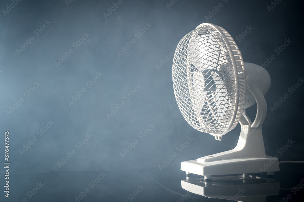 Side view of a white electric desktop fan on a black background and ...