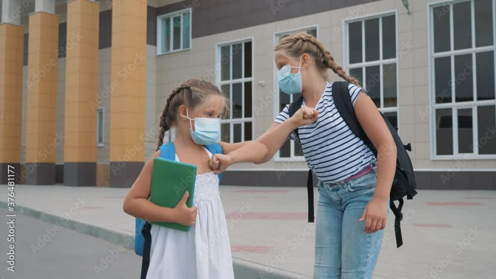 Schoolgirls sit in the park on a bench wearing medical masks and say ...