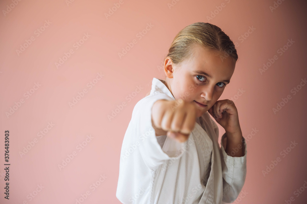 Little girl in karate suit kimono in studio at pink background. Female ...
