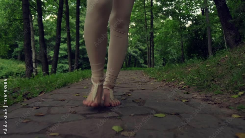 Barefoot female feet walk along the stone path. Around the forest ...