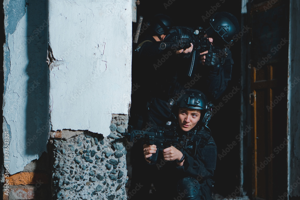 Special forces soldiers in black uniform aiming with a rifle from the ...