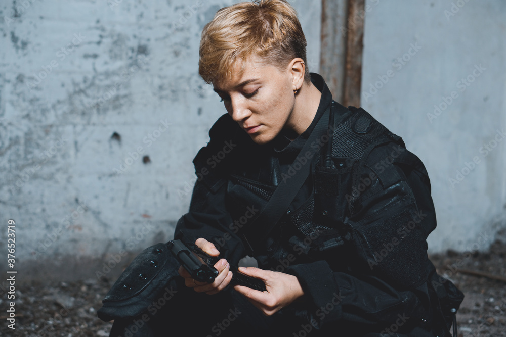 Young woman soldier in black uniform reloading the pistol. Stock Photo ...