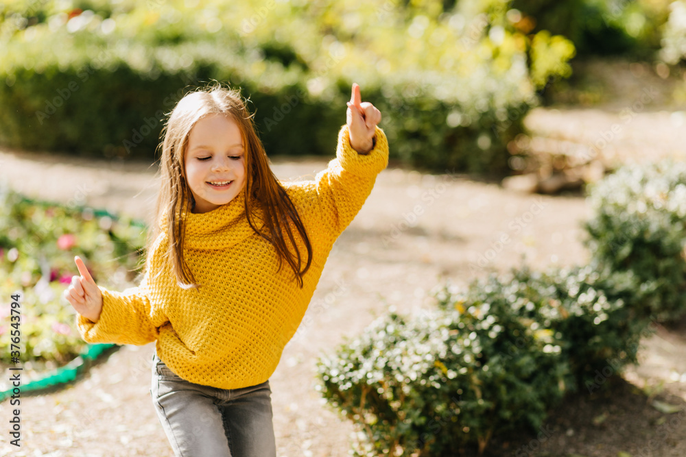Good-humoured kid in sweater dancing on nature background. Outdoor ...