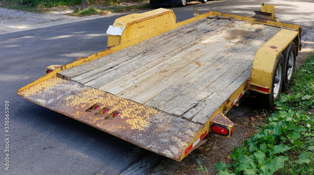 Rear view of weathered empty flatbed trailer parked on street in ...