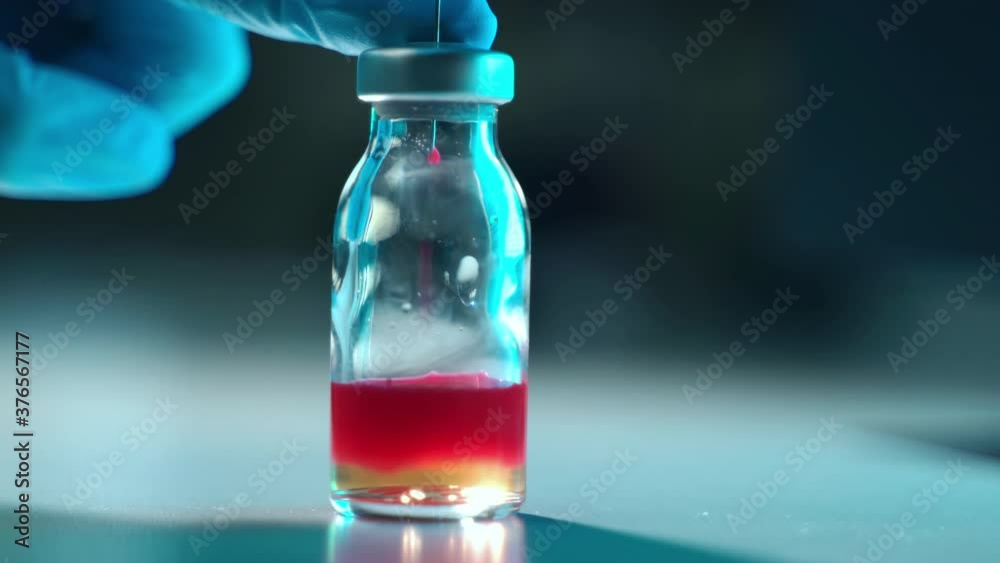 Red chemical solution dropping from sterile syringe inside the ...