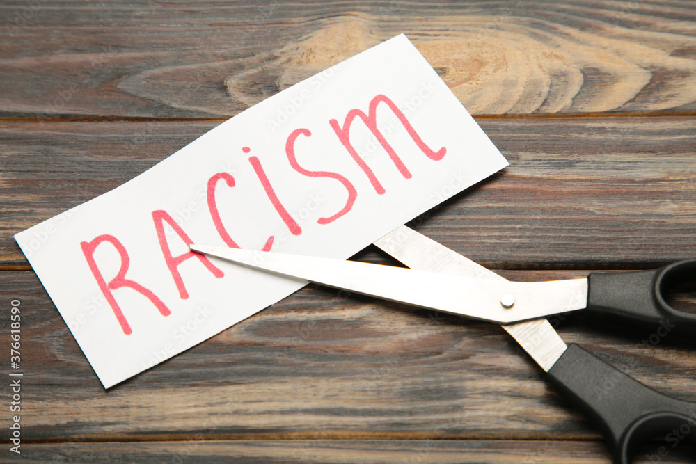 Top view of black scissors and cutted paper card with word Racism on ...