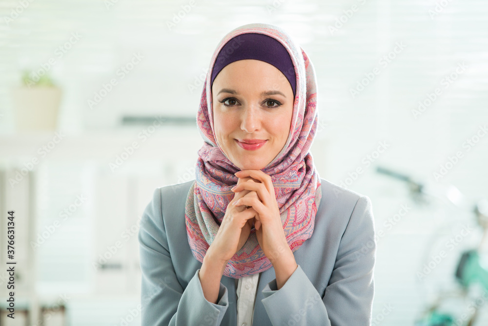 Beautiful young working woman in hijab and suit sitting in office ...