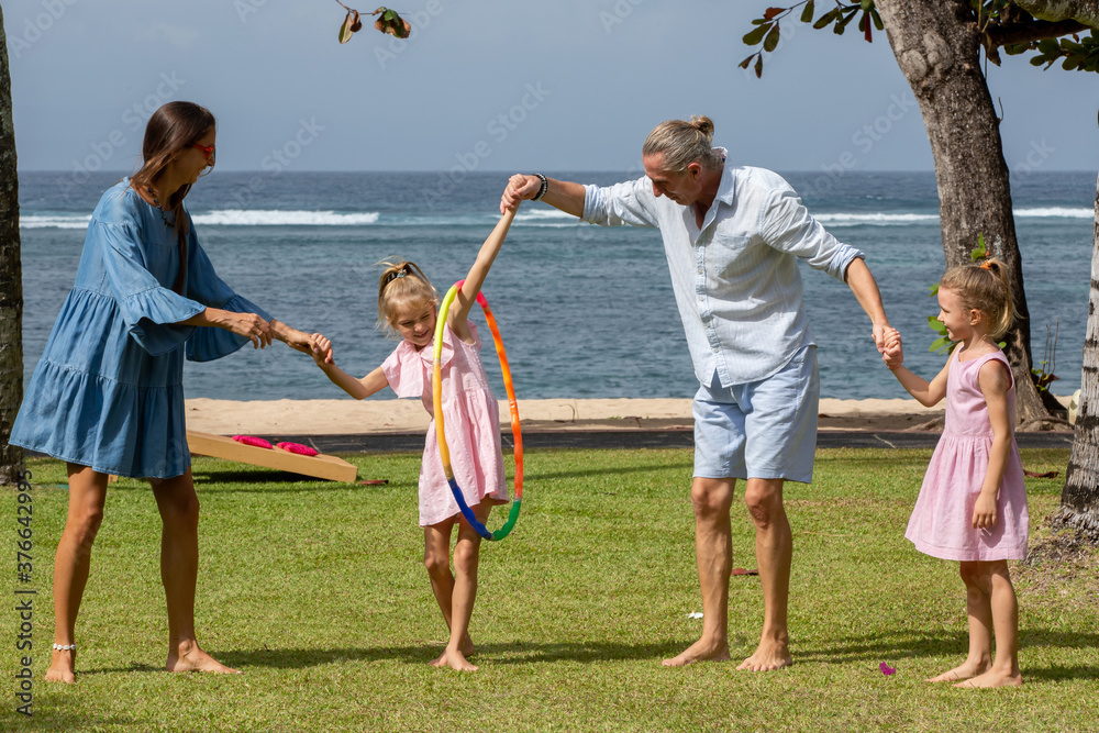 Parents playing exciting hula hoop pass game with children by the sea ...