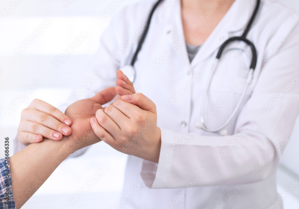 While examining the patients' pulse by hand, the female doctor talks to ...