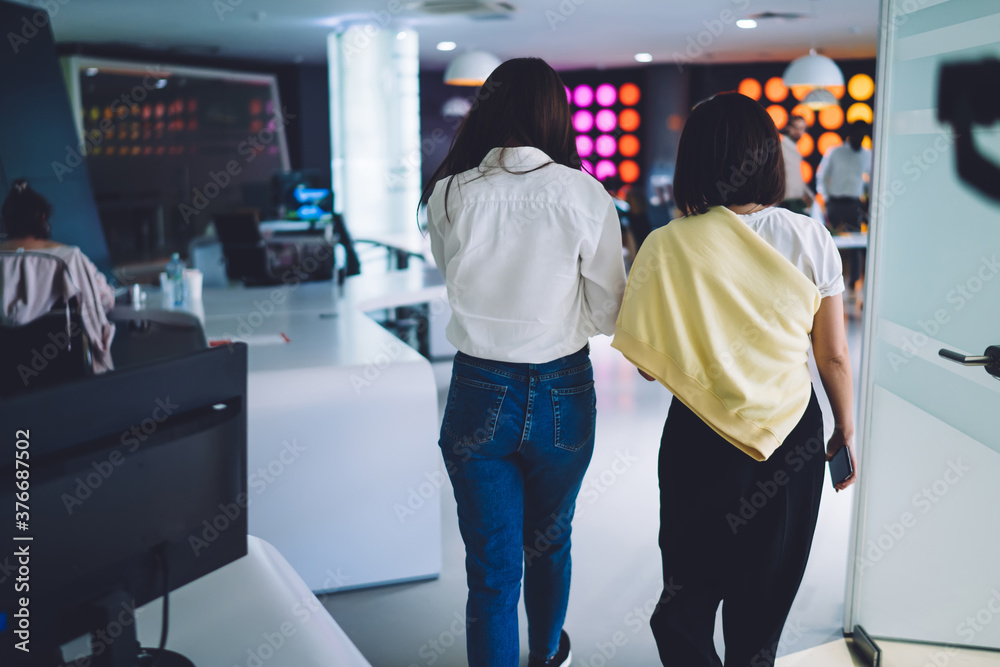 Back view of female employees walking i modern office interior having ...