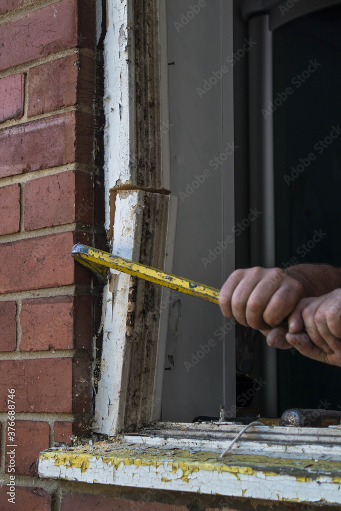 Crowbar being used to remove an old wooden window frame in brick wall ...