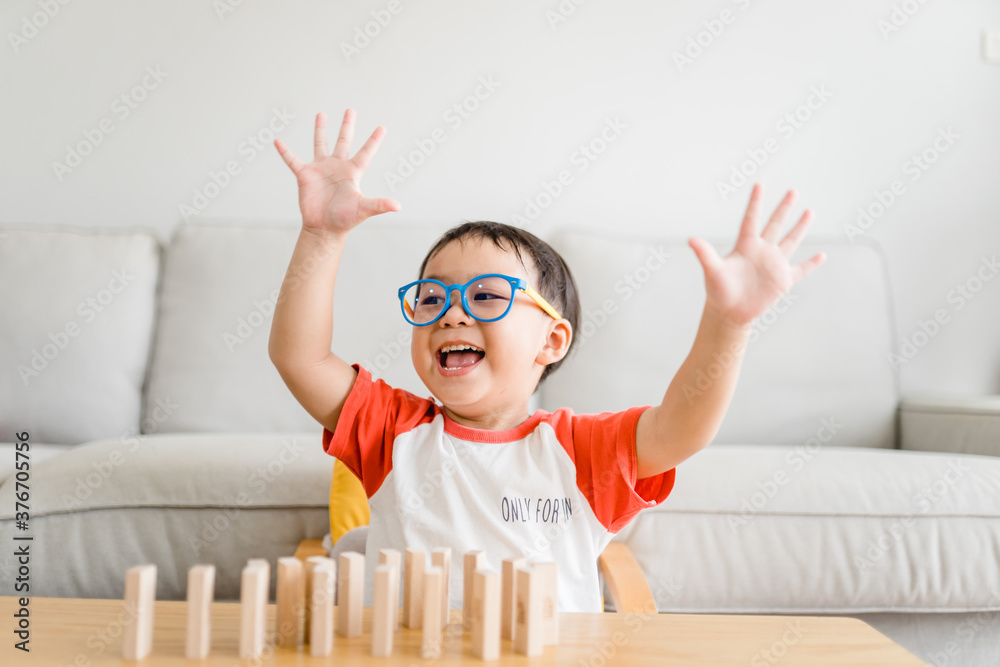 Happy smart and nerd toddler asian boy raised hand when he win play ...