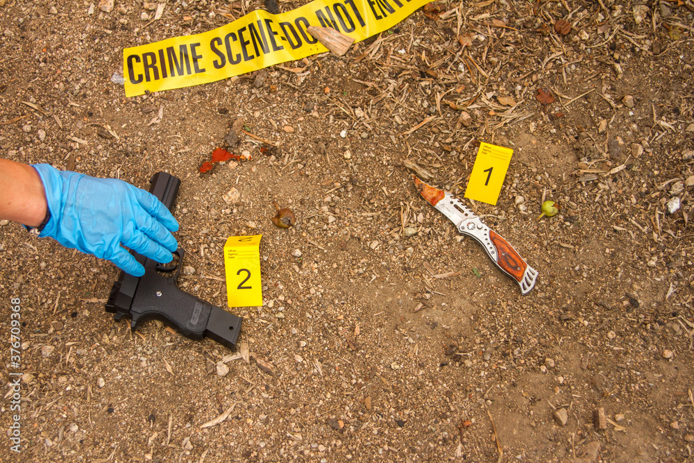 close up of a detective hand removing evidence of the crime like gun or ...