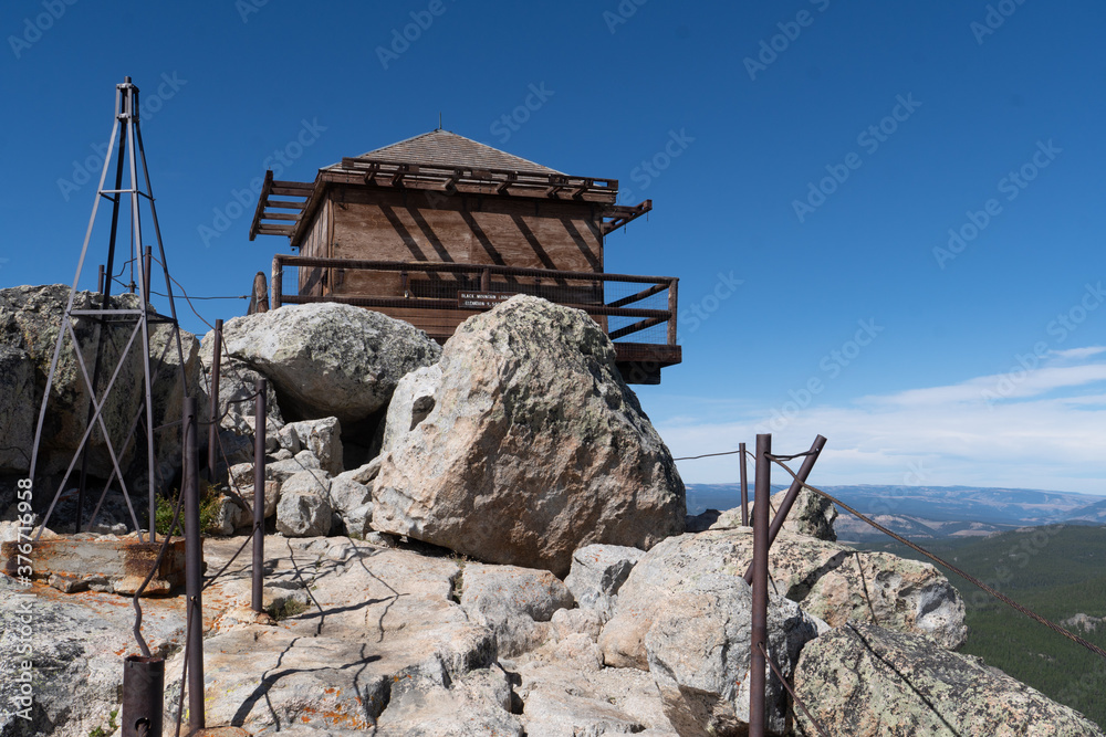 A square wooden building at a top of a bare rock outcropping ...