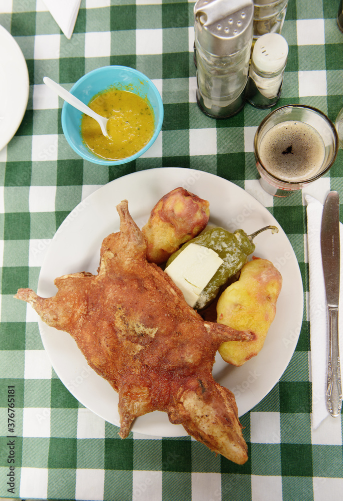 Table with meal of roasted guinea pig with potato, green pepper and ...