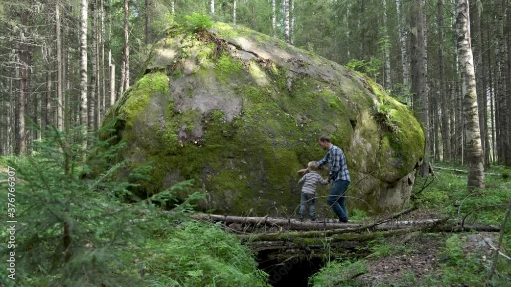 Family tourists father and son walking near huge boulder covered by ...