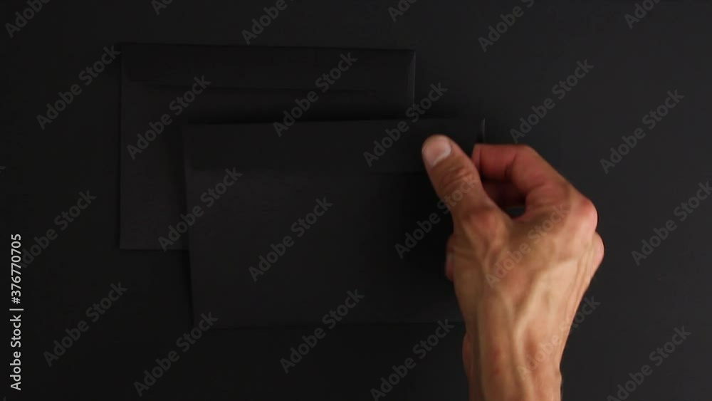 caucasian male hand take three strange blank black envelopes from black ...