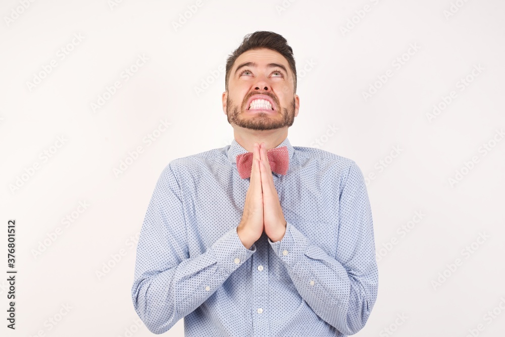 European man dressed in formal shirt and bow tie poses against white ...
