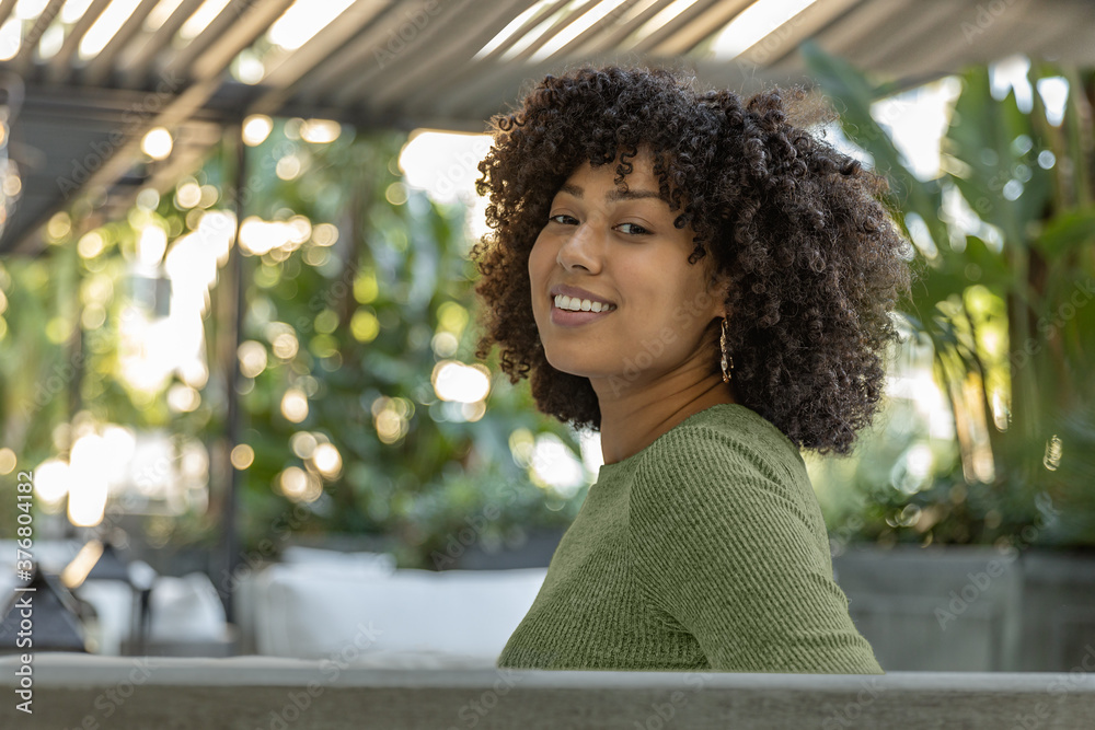 The beautiful, youthful lady looks over her shoulder and with a smile ...