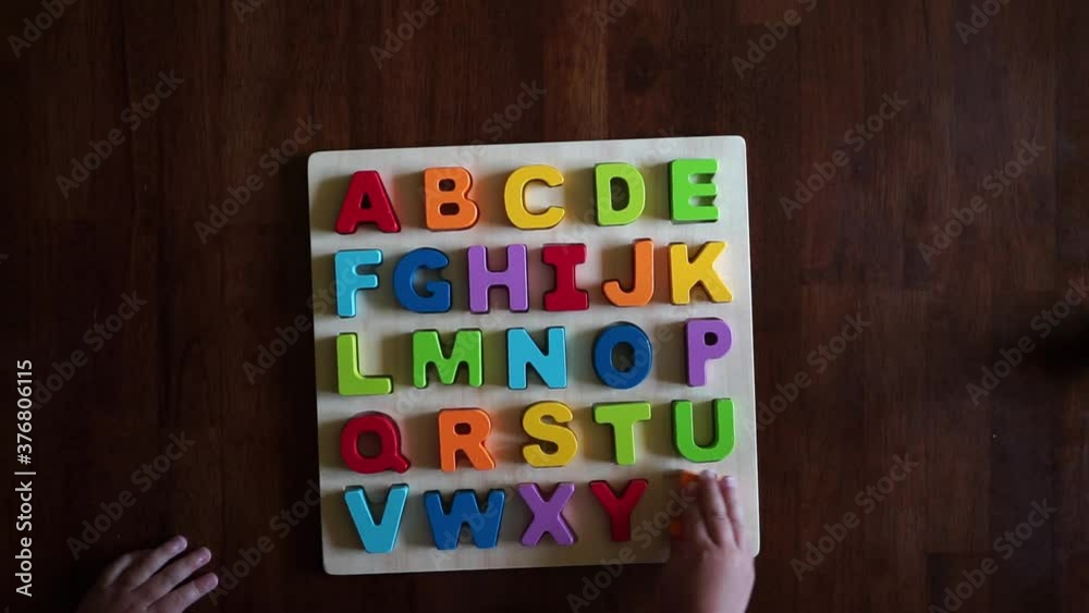 Toddler hands placing letter Z to complete an alphabet puzzle. Static ...