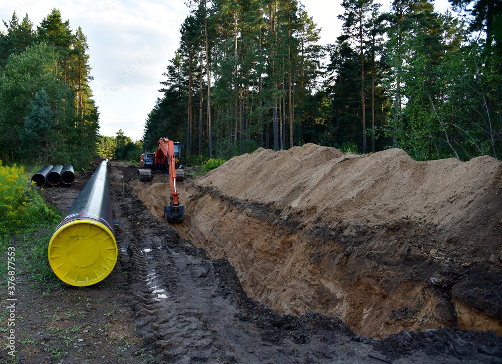 Excavator digging trench in ground for laying pipeline of natural gas ...