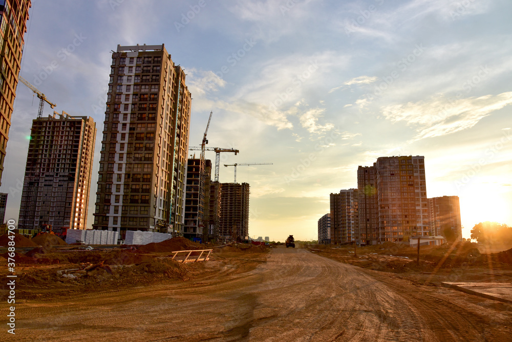 Tower cranes working at construction site on sunset background ...
