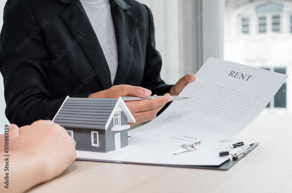 A real estate agent with a home model is talking to clients about ...