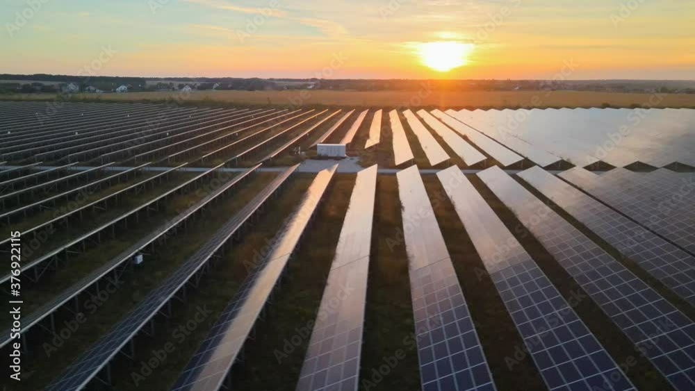 Aerial drone view into large solar panels at a solar farm at bright ...