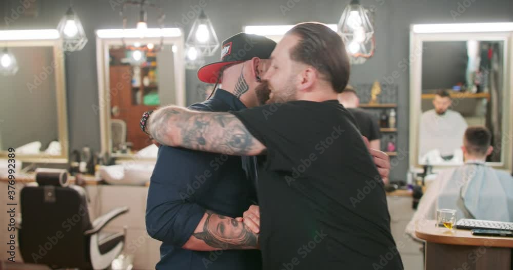 Two young bearded and mustashed men, with tattoed hands, are shaking ...