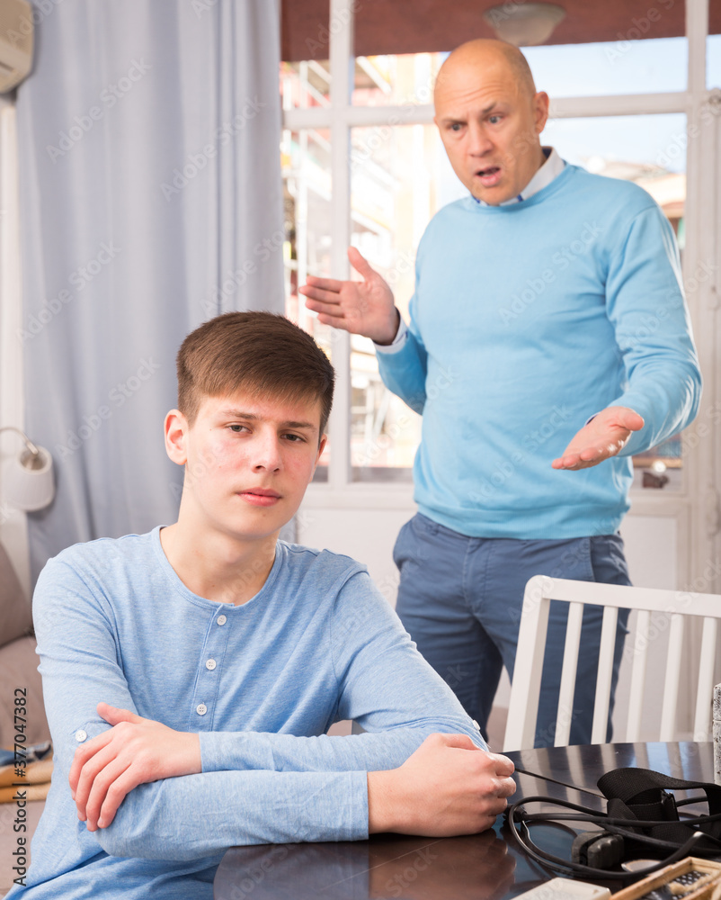 Angry father scolding his turned away son teenager at home Stock Photo ...